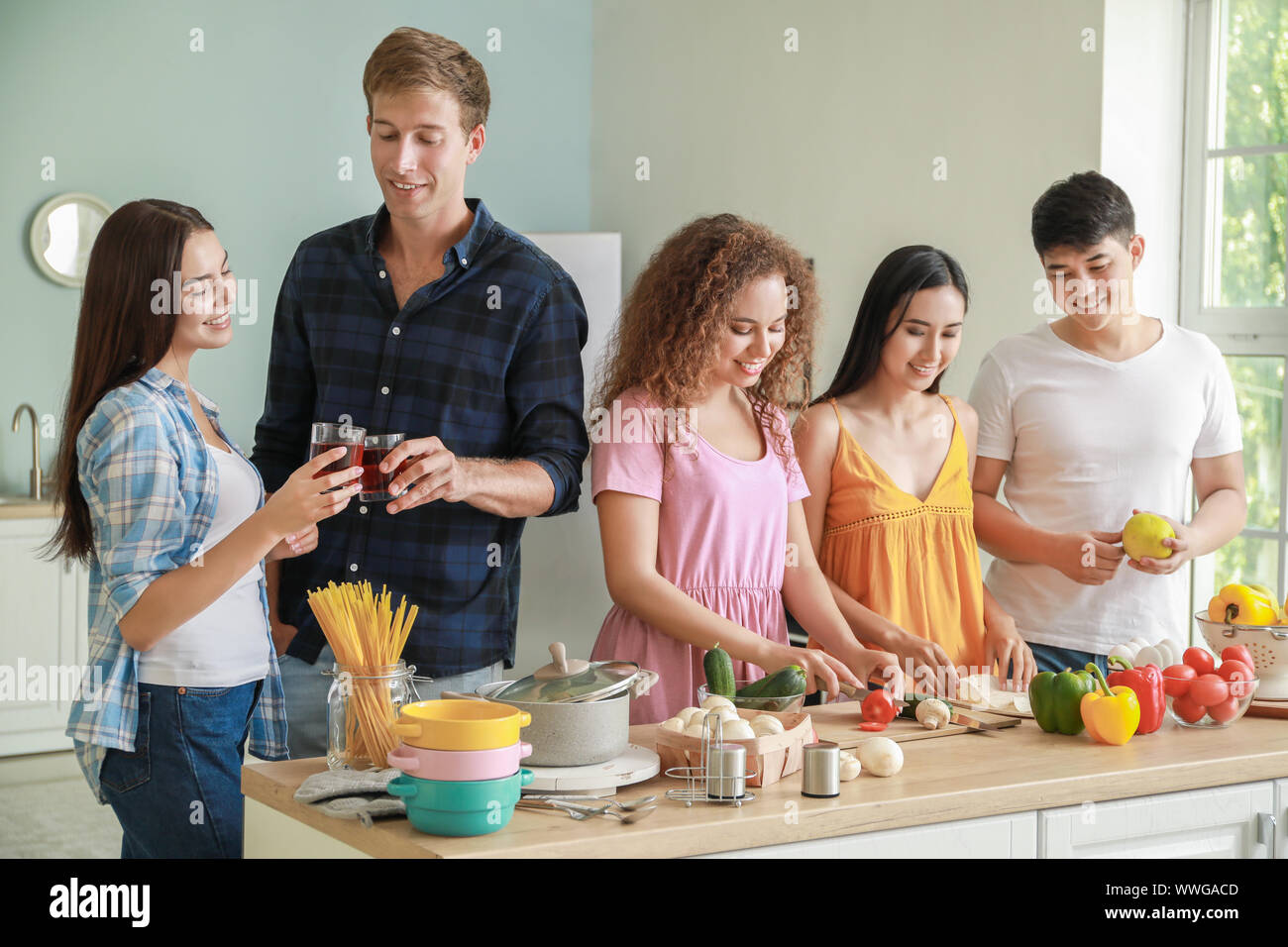 Happy friends cooking together in kitchen Stock Photo - Alamy