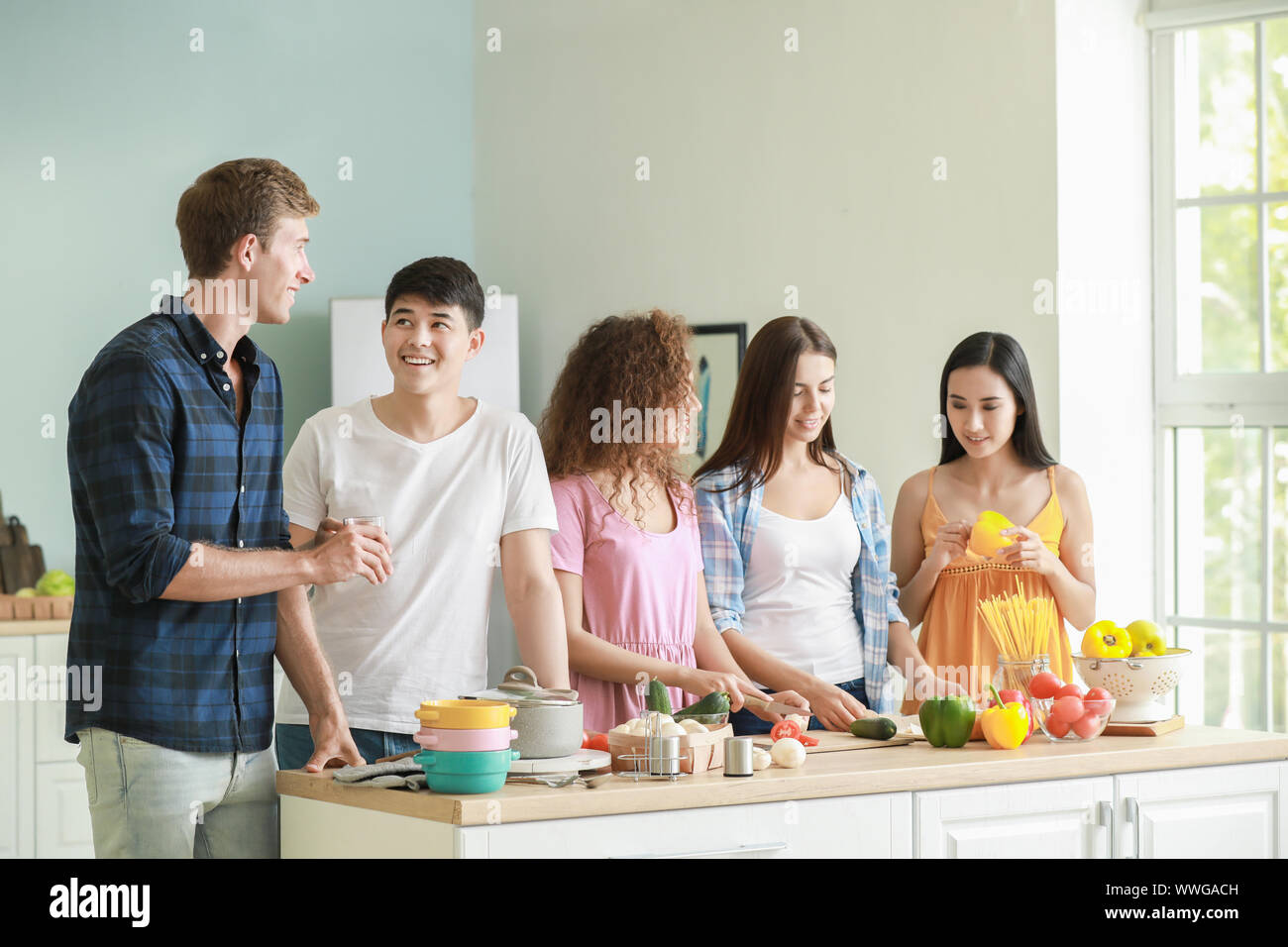 Happy friends cooking together in kitchen Stock Photo - Alamy