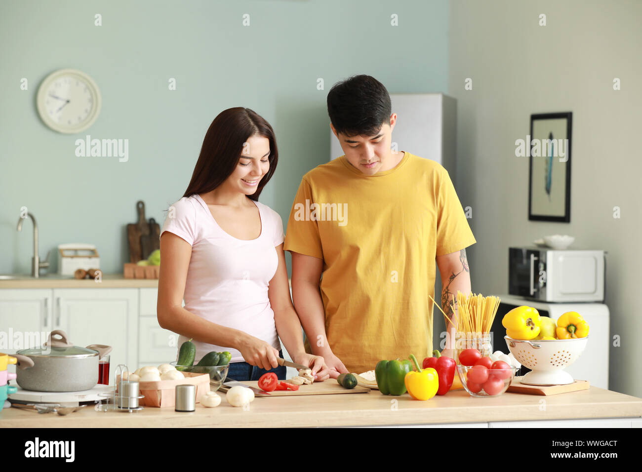 Happy couple cooking together in kitchen Stock Photo - Alamy