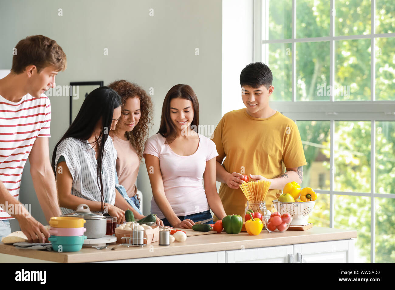 Happy friends cooking together in kitchen Stock Photo - Alamy
