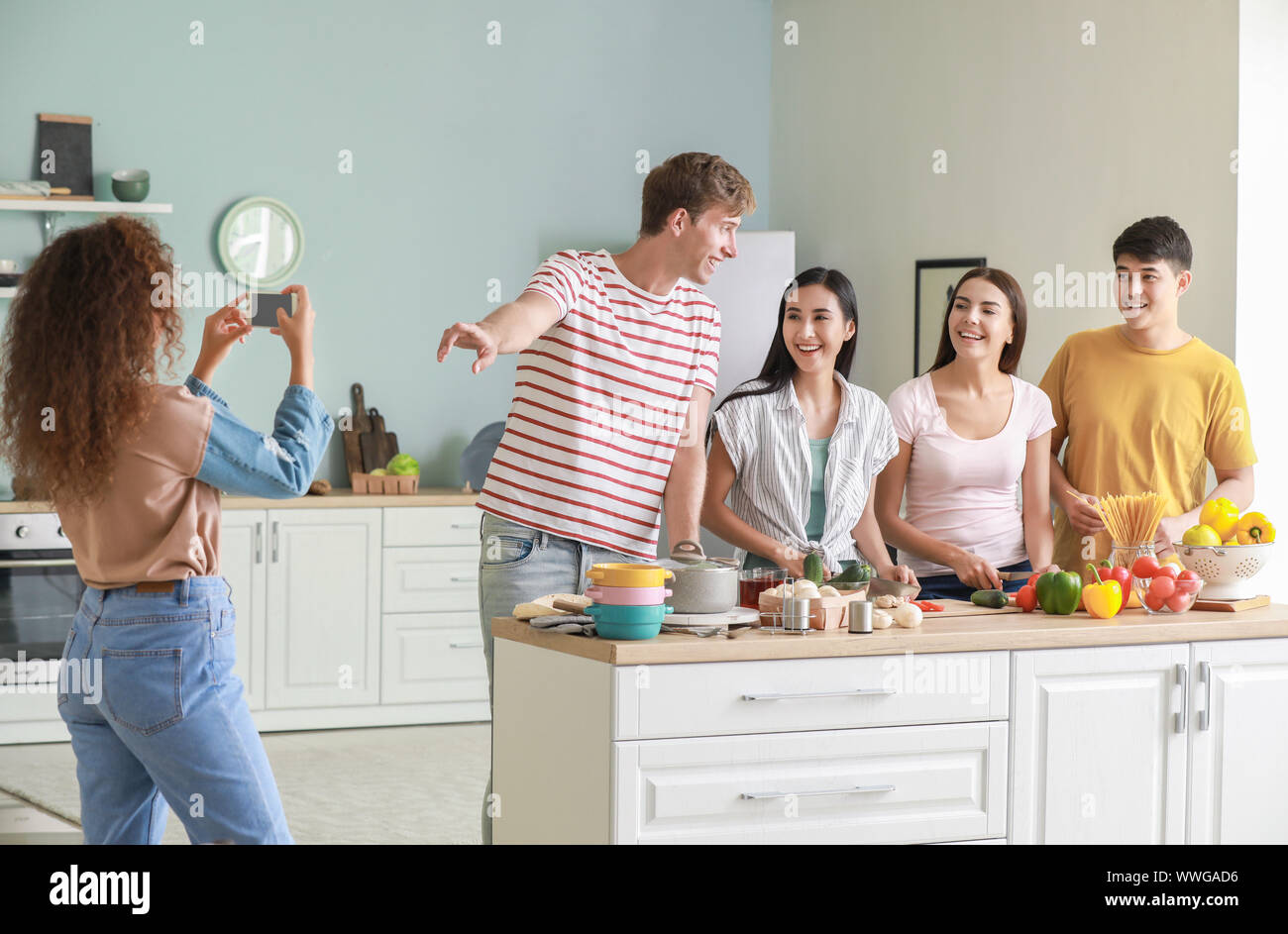 African-American woman taking photo of her friends cooking in kitchen ...