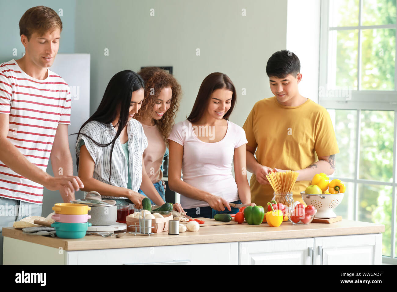 Happy friends cooking together in kitchen Stock Photo - Alamy