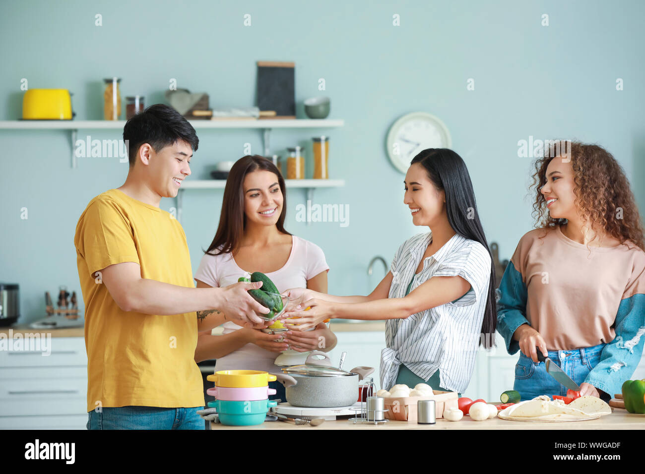 Happy friends cooking together in kitchen Stock Photo - Alamy