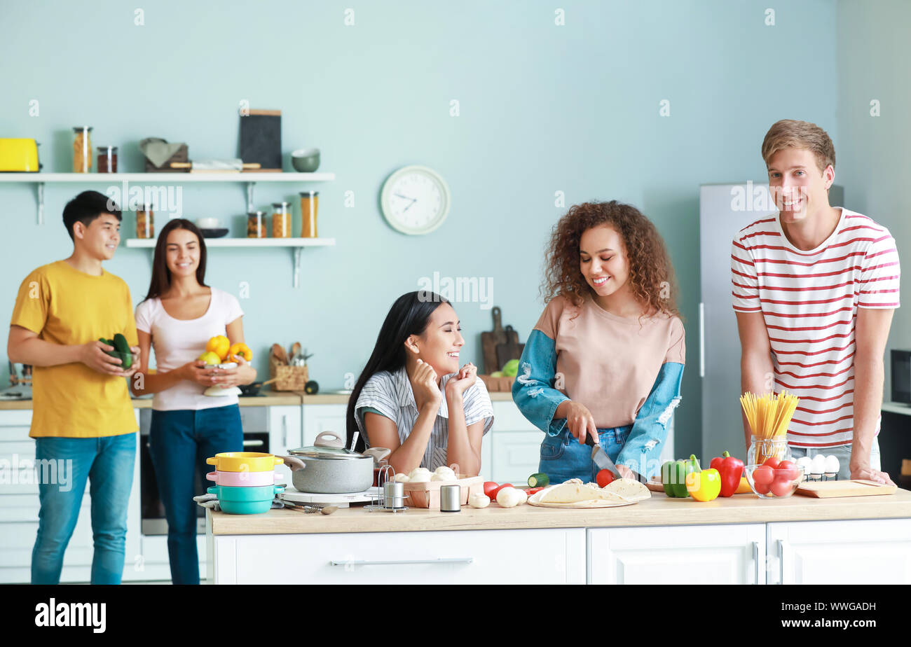 Happy friends cooking together in kitchen Stock Photo - Alamy