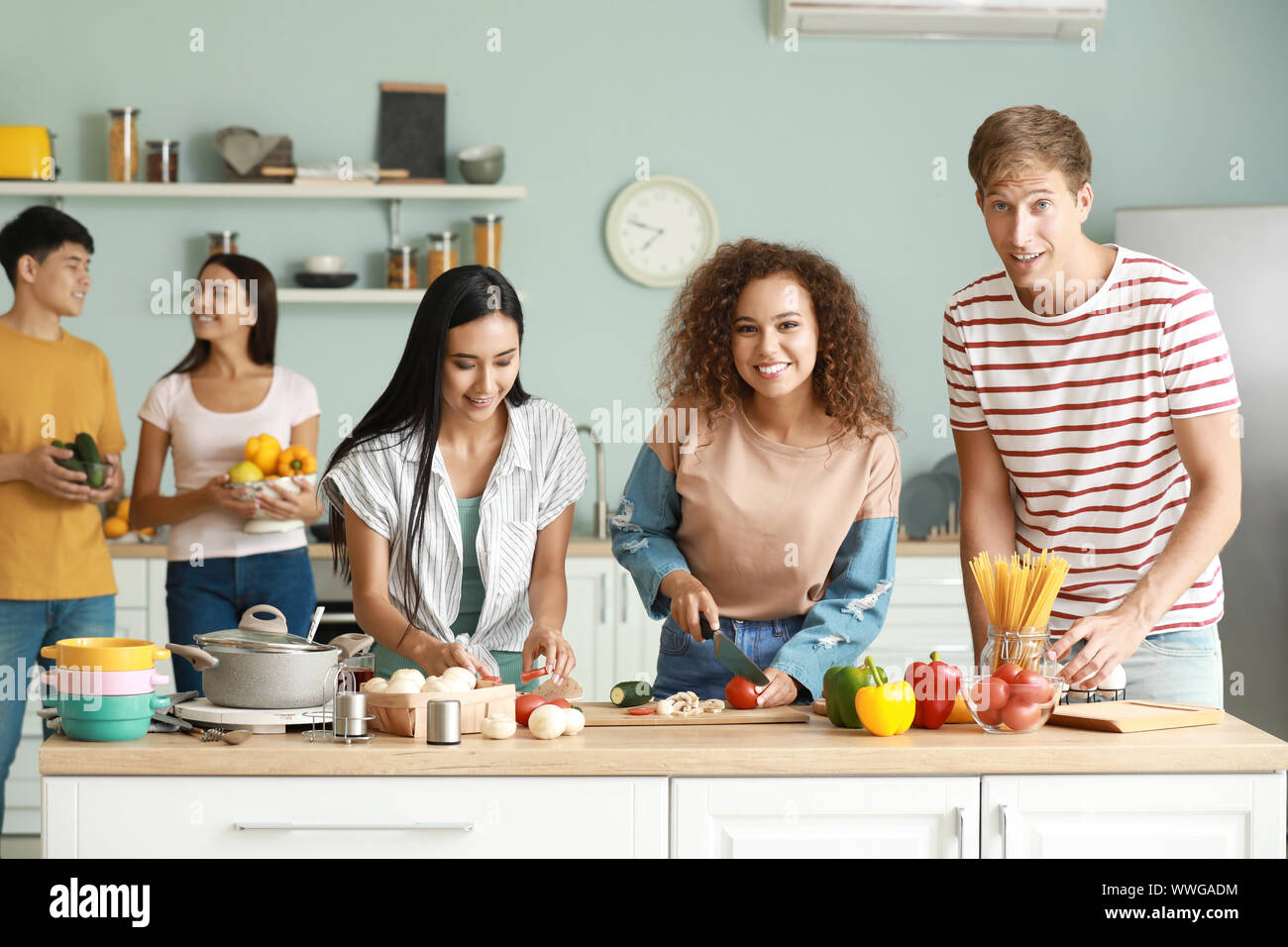 Happy friends cooking together in kitchen Stock Photo - Alamy
