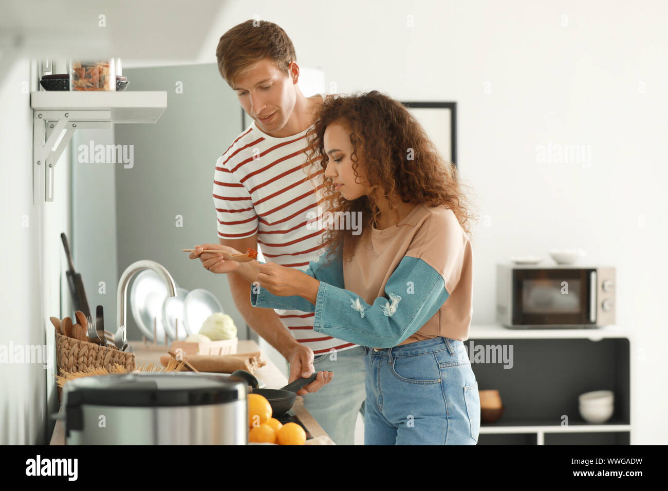 Happy couple cooking together in kitchen Stock Photo - Alamy