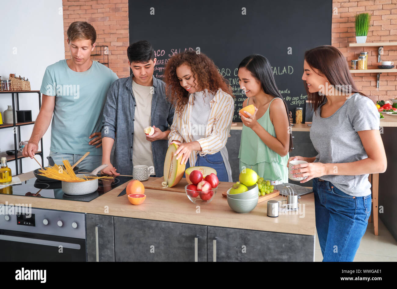 Happy friends cooking together in kitchen Stock Photo - Alamy
