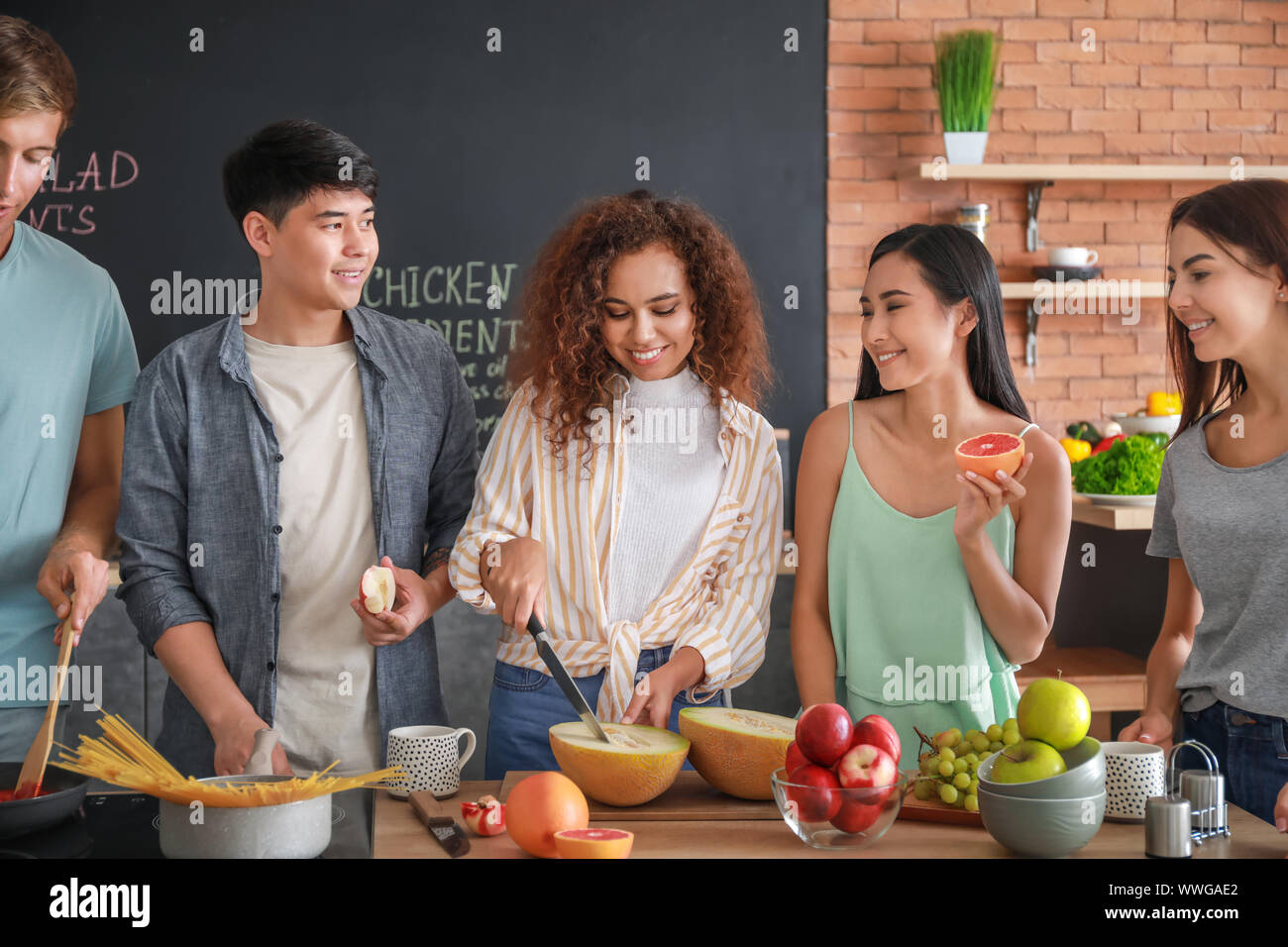 Happy friends cooking together in kitchen Stock Photo - Alamy