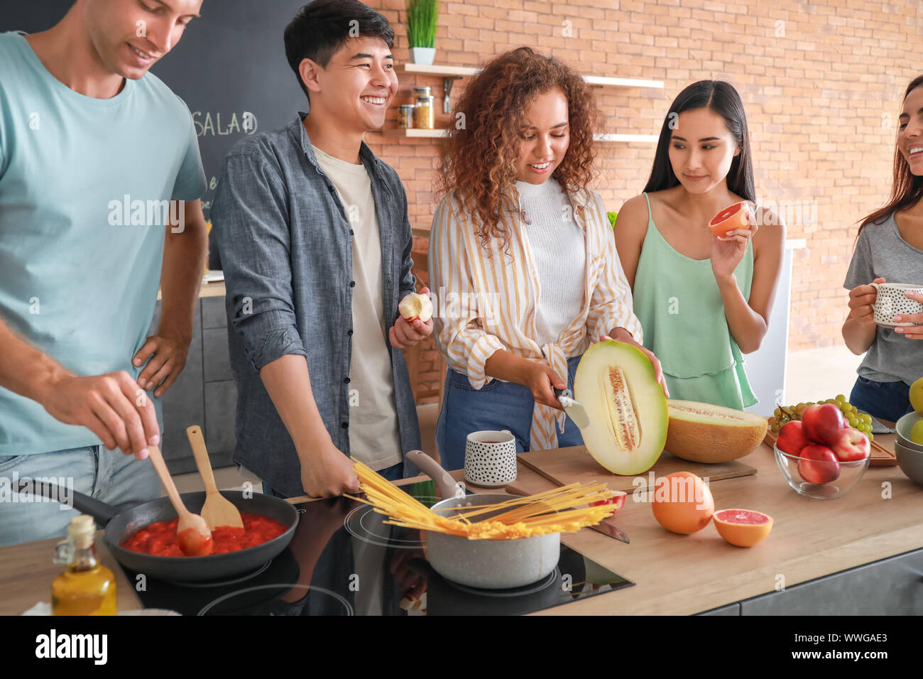 Happy friends cooking together in kitchen Stock Photo - Alamy