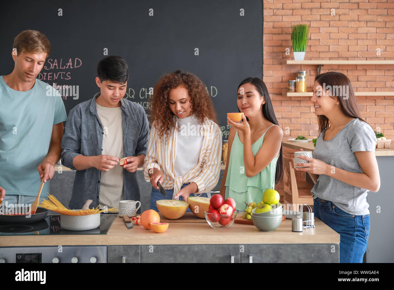 Happy friends cooking together in kitchen Stock Photo - Alamy