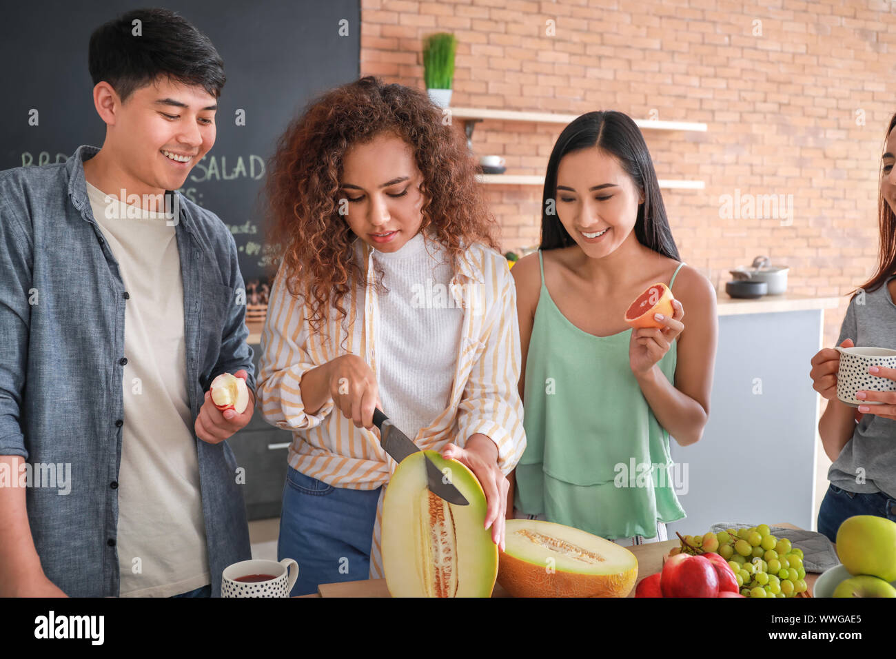 Happy friends cooking together in kitchen Stock Photo - Alamy