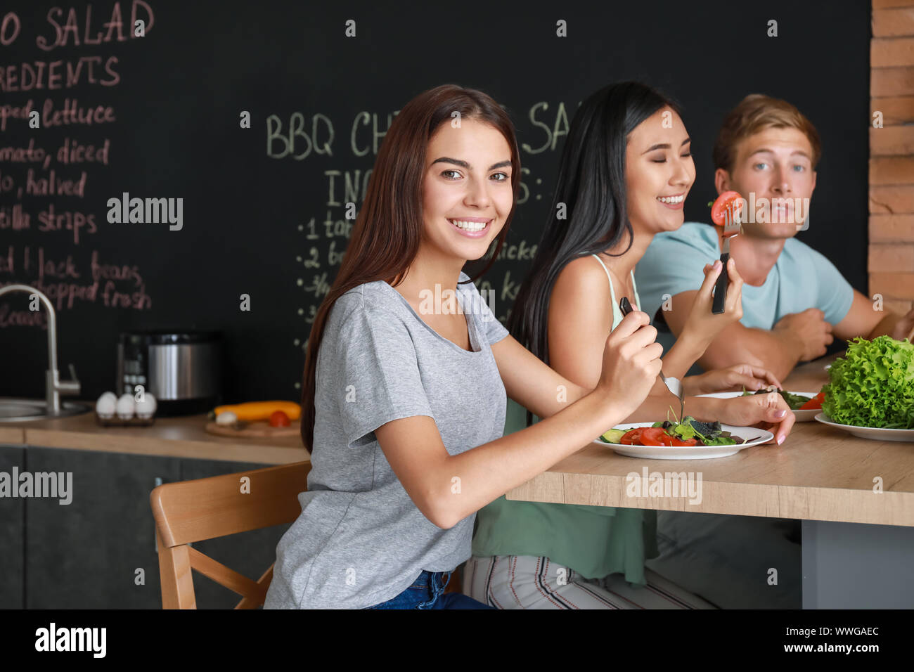 Happy friends eating together in kitchen Stock Photo - Alamy