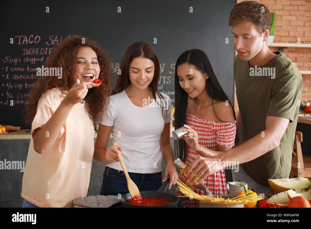 Happy friends cooking together in kitchen Stock Photo - Alamy