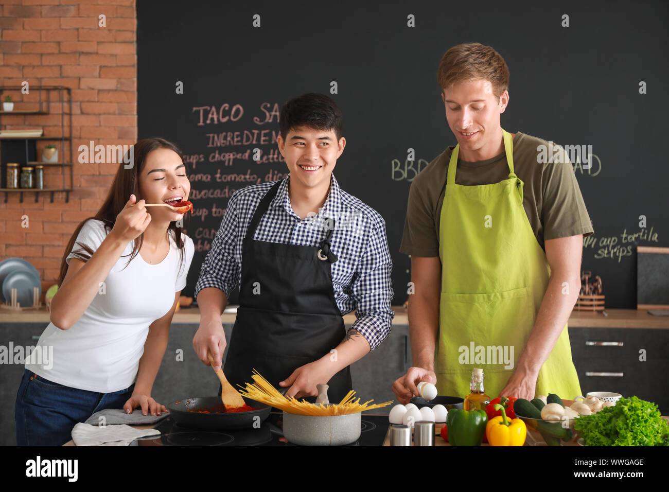 Happy friends cooking together in kitchen Stock Photo - Alamy