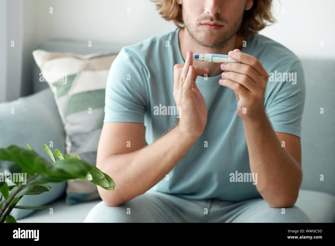 Diabetic man taking blood sample with lancet pen at home Stock Photo ...