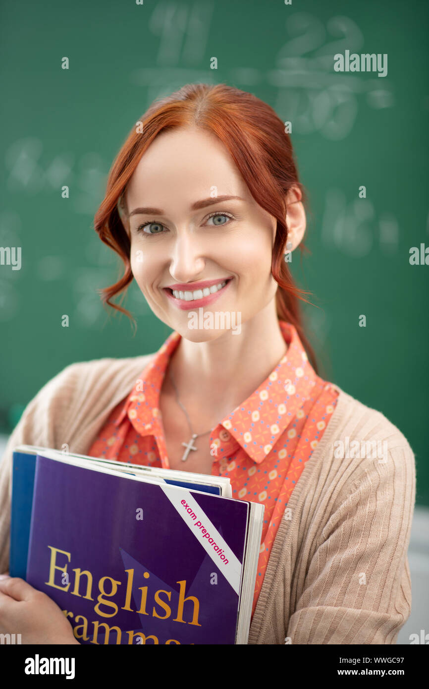 Teacher holding book while standing near blackboard Stock Photo - Alamy