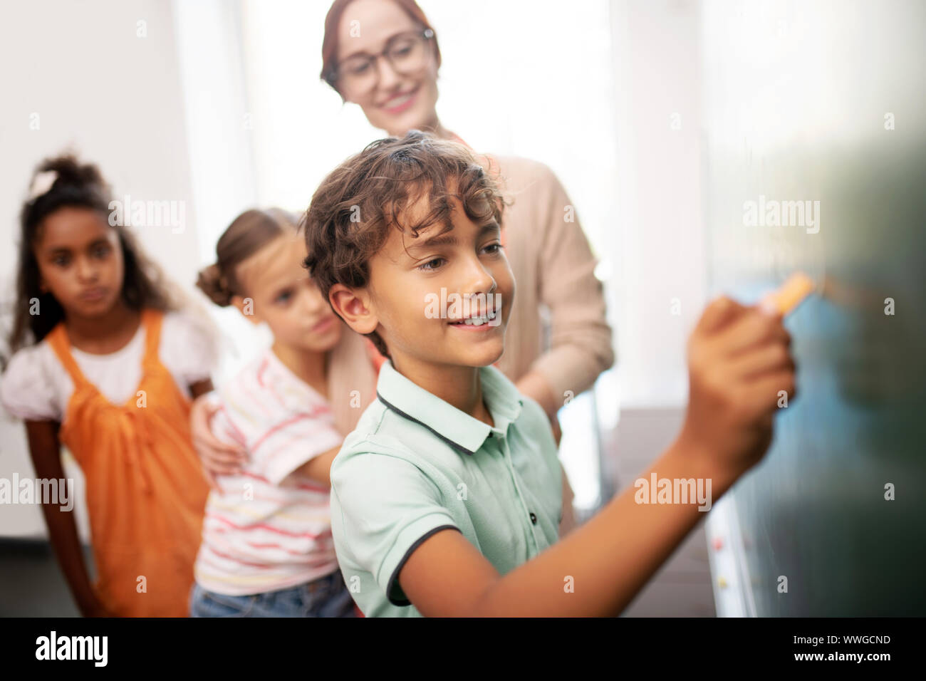 Boy coming to blackboard during math class Stock Photo - Alamy