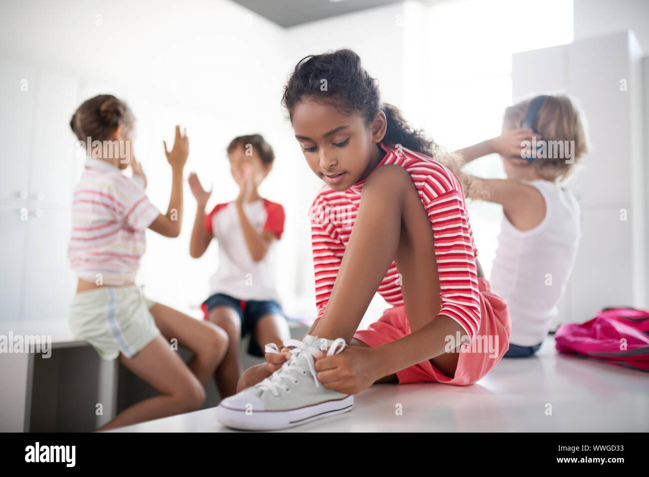 Dark-skinned girl lacing her sneakers getting ready for PE class Stock ...