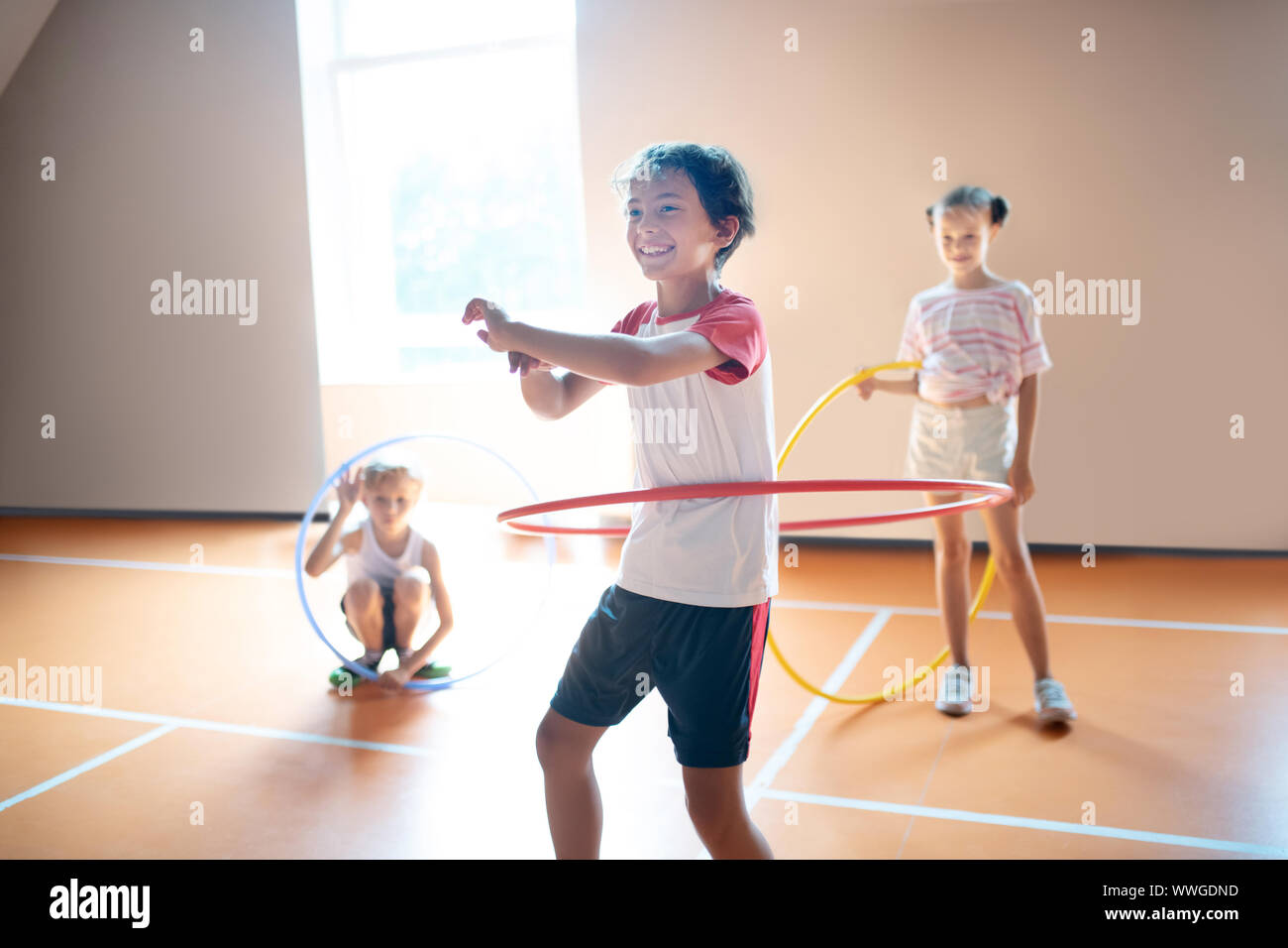 Boy laughing while rolling hula-hoop for the first time Stock Photo - Alamy