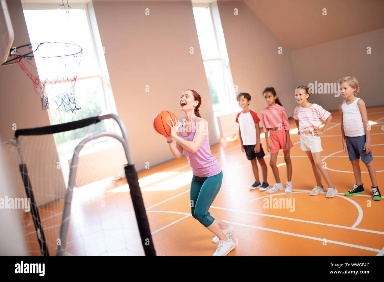 Red-haired PE teacher throwing ball into basket Stock Photo - Alamy