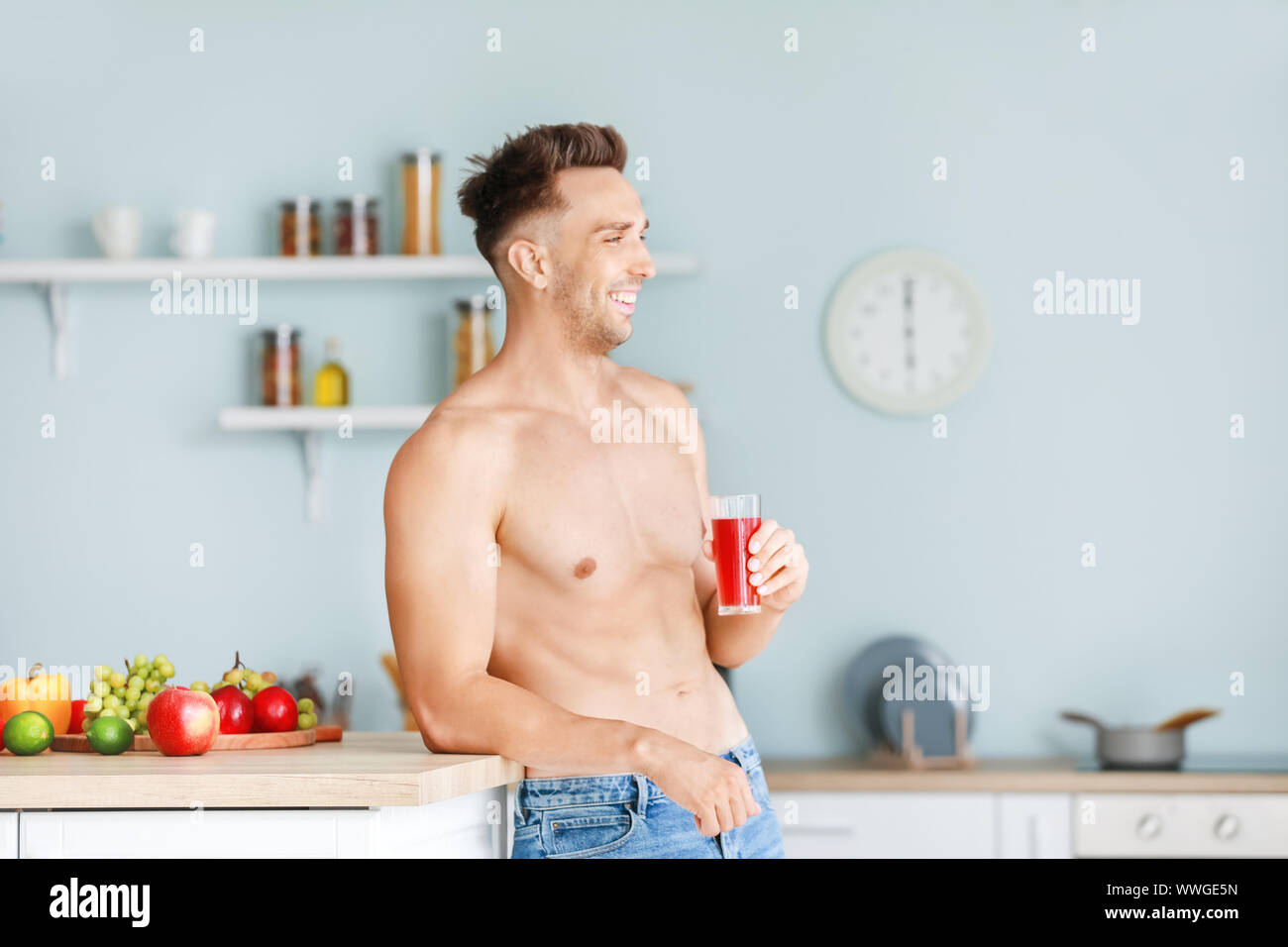 Handsome muscular man drinking juice in kitchen. Weight loss concept ...