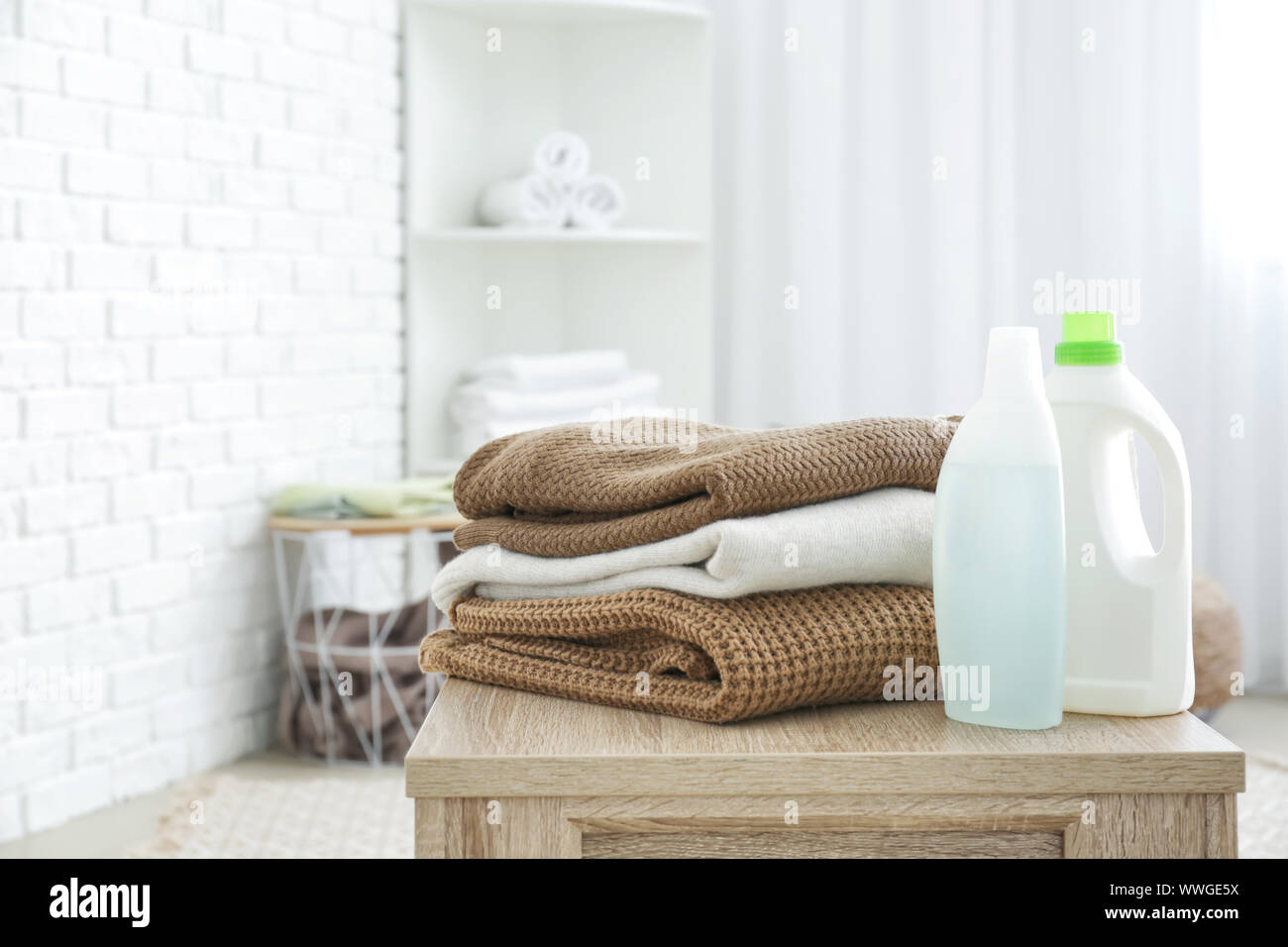 Stack of clean clothes and washing agents on table in bathroom Stock ...