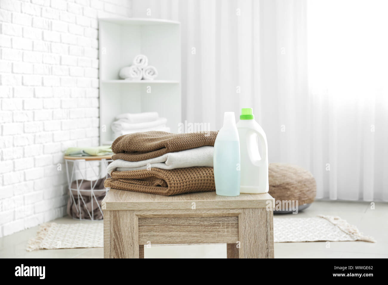 Stack of clean clothes and washing agents on table in bathroom Stock ...