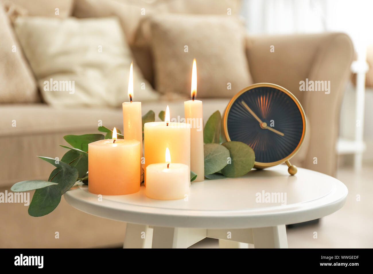 Beautiful burning candles and clock on table Stock Photo - Alamy