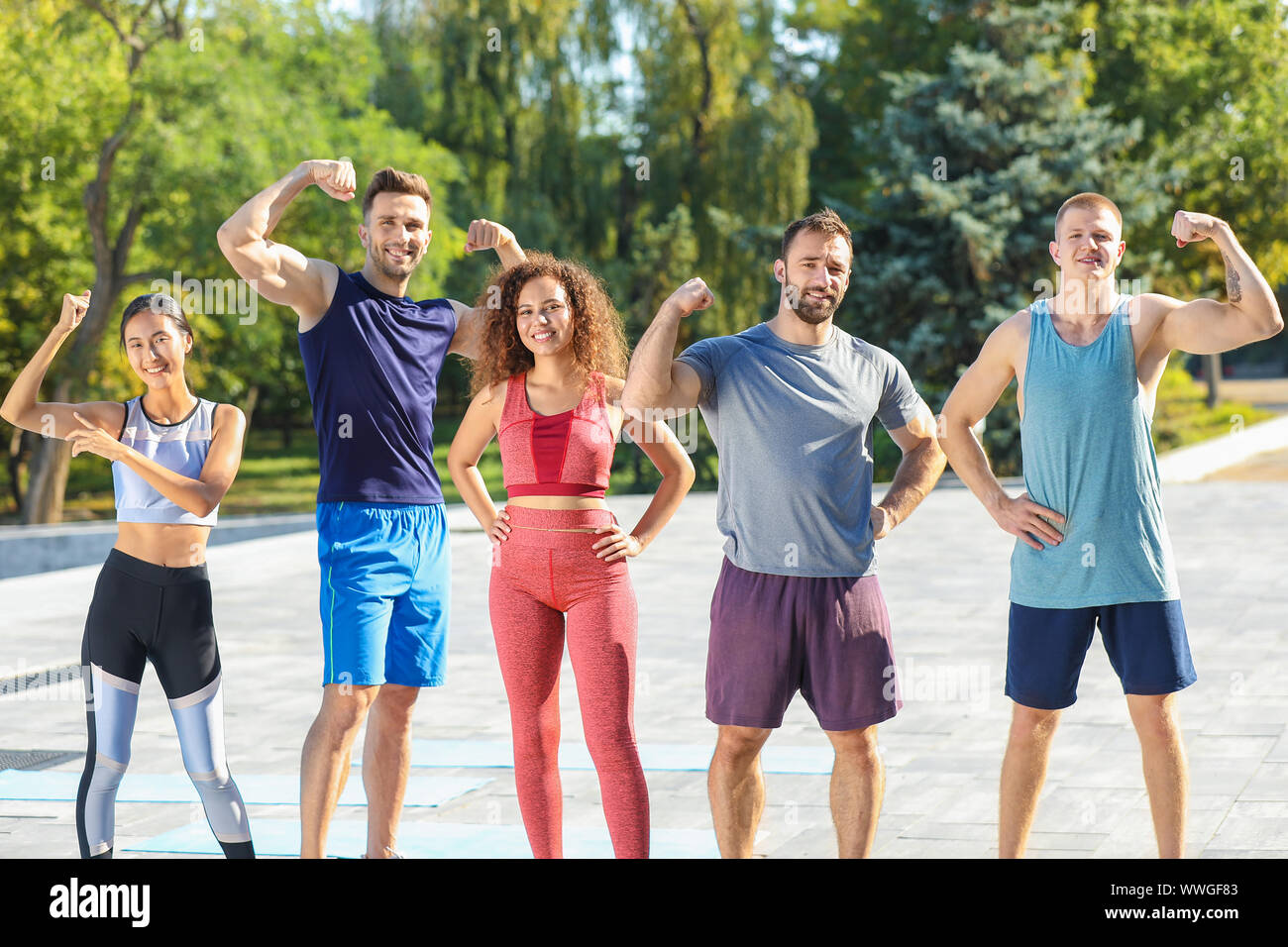 Group of young sporty people showing muscles outdoors Stock Photo - Alamy