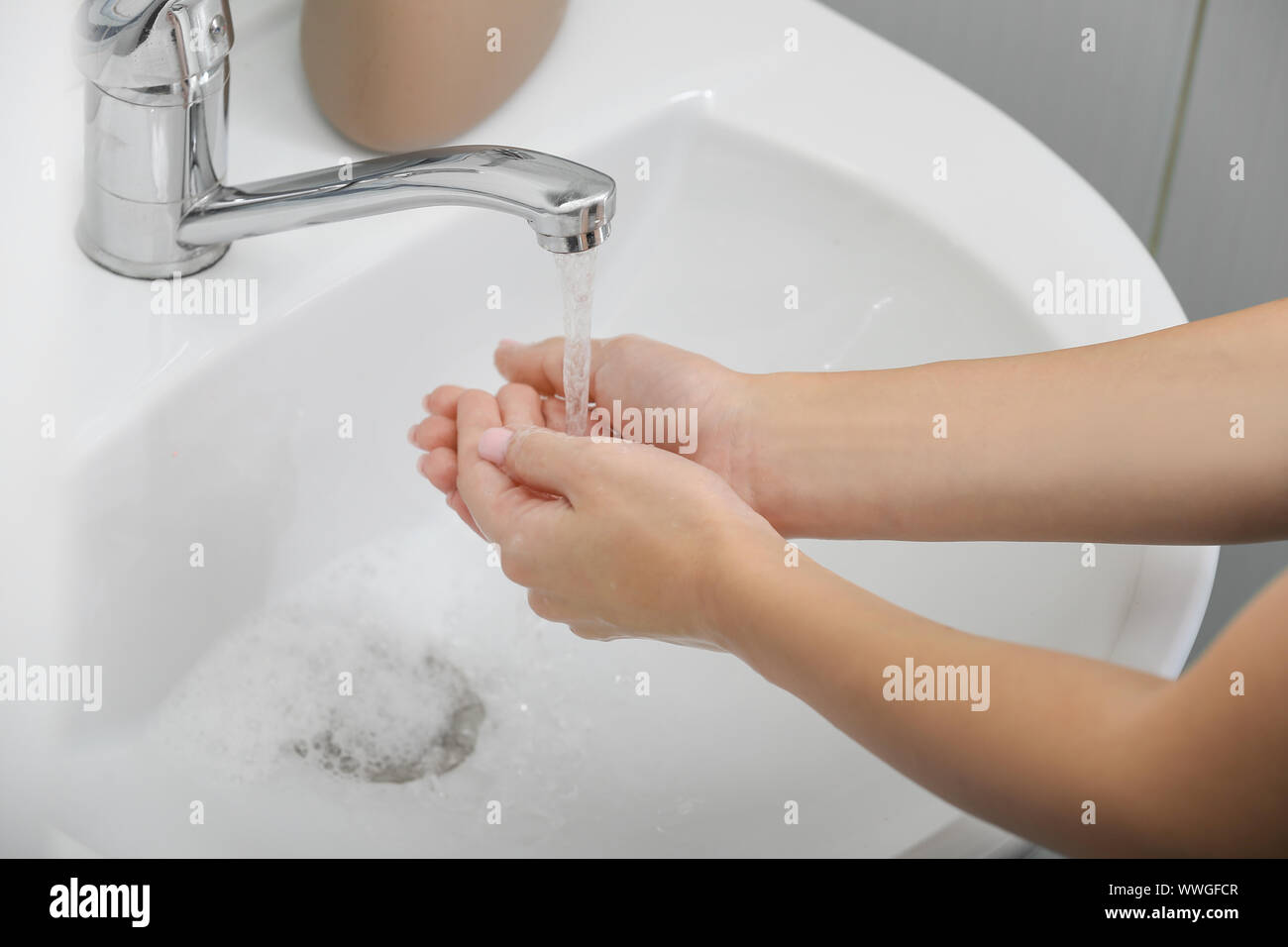Young woman washing hands in sink Stock Photo - Alamy