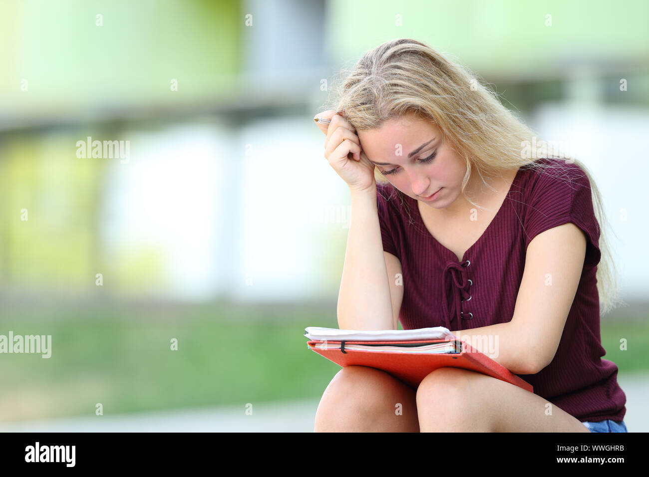 Serious student studying memorizing notes sitting outdoors in an ...