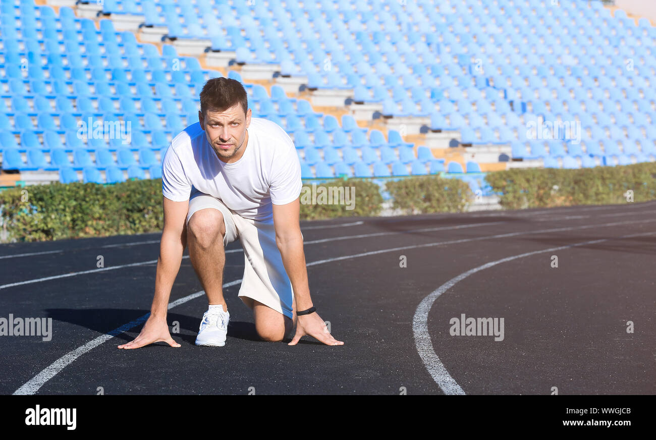 Sporty man in crouch start position at the stadium Stock Photo - Alamy