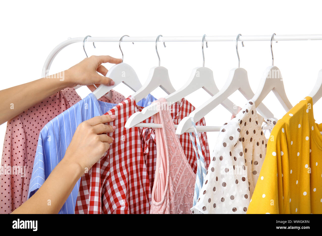 Woman choosing clothes hanging on rack against white background Stock ...