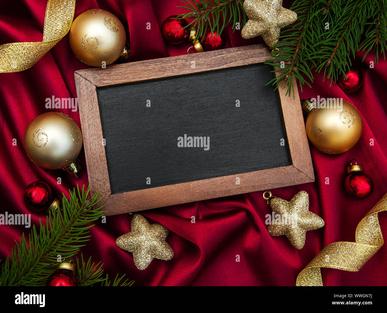 Christmas holiday background - blackboard and baubles on a red silk ...