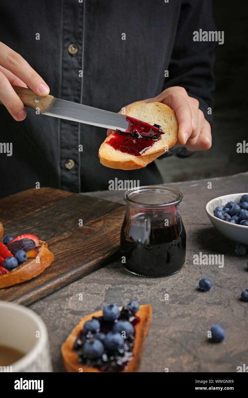 Woman spreading tasty berry jam onto toasted bread, closeup Stock Photo ...