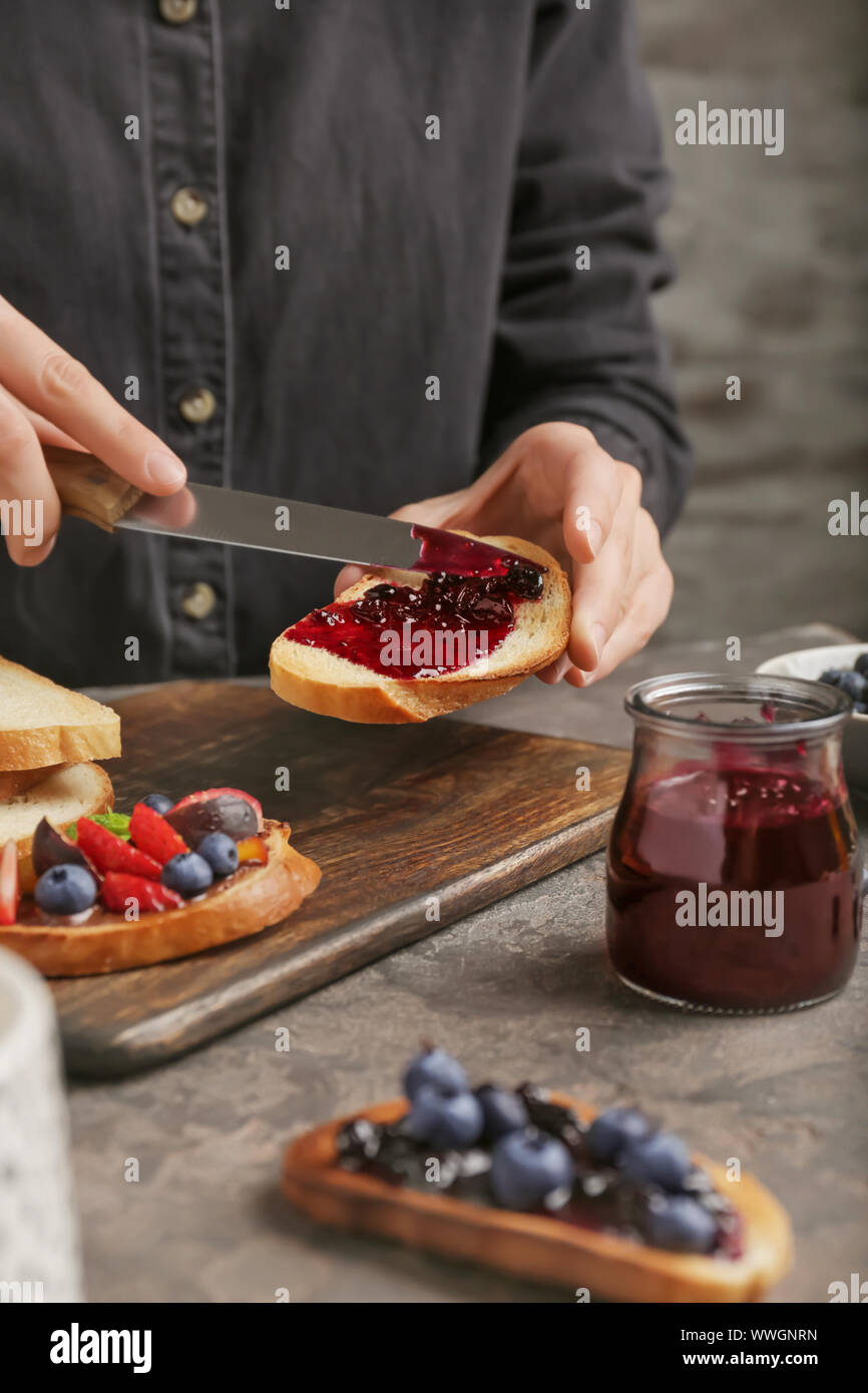 Woman spreading tasty berry jam onto toasted bread, closeup Stock Photo ...