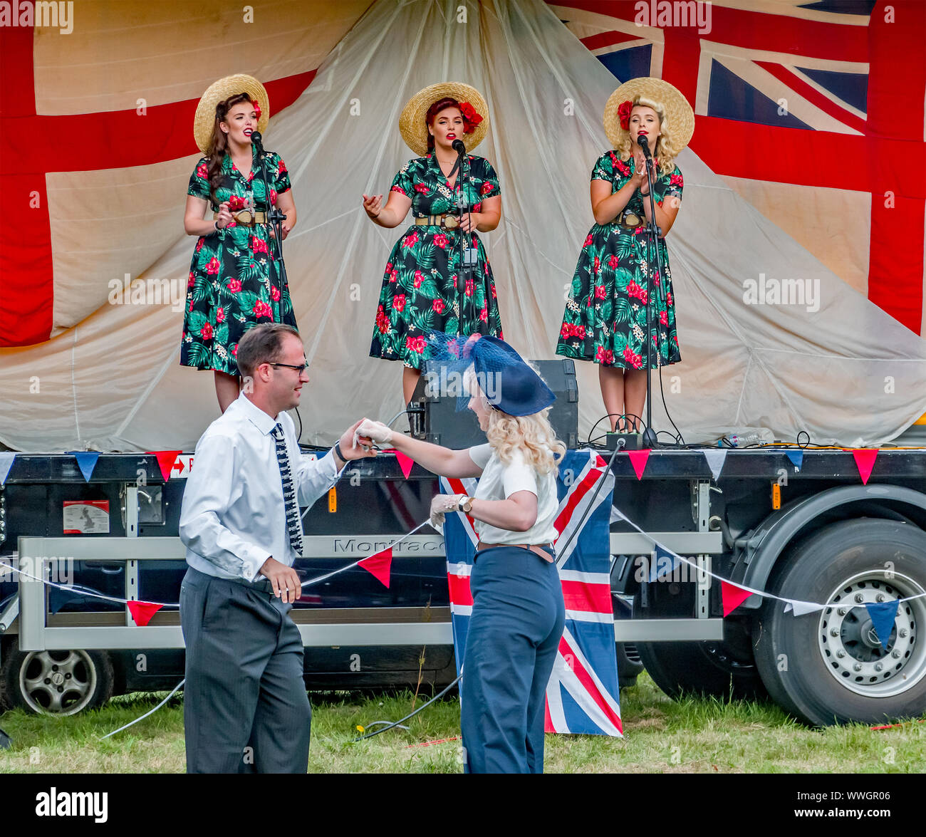 A couple dressed up in 1940s style clothing dancing whilst a female ...