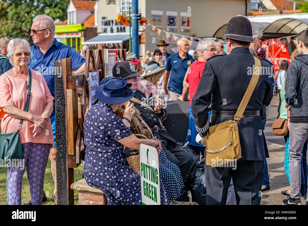 A man dressed as a 1940s policeman sat on a bench eating an ice cream ...