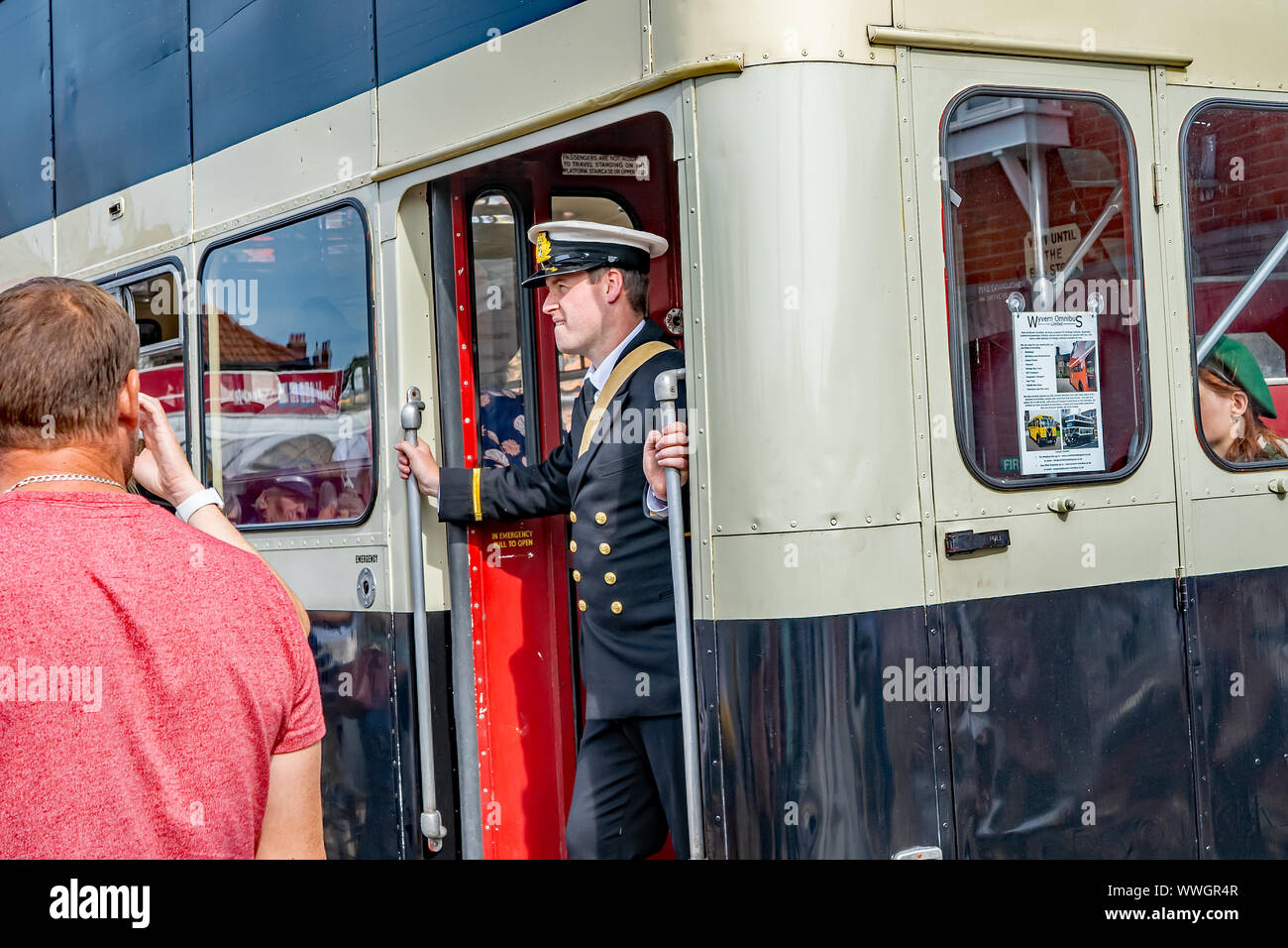 A young male dressed in vintage clothing as a bus conductor on board a ...