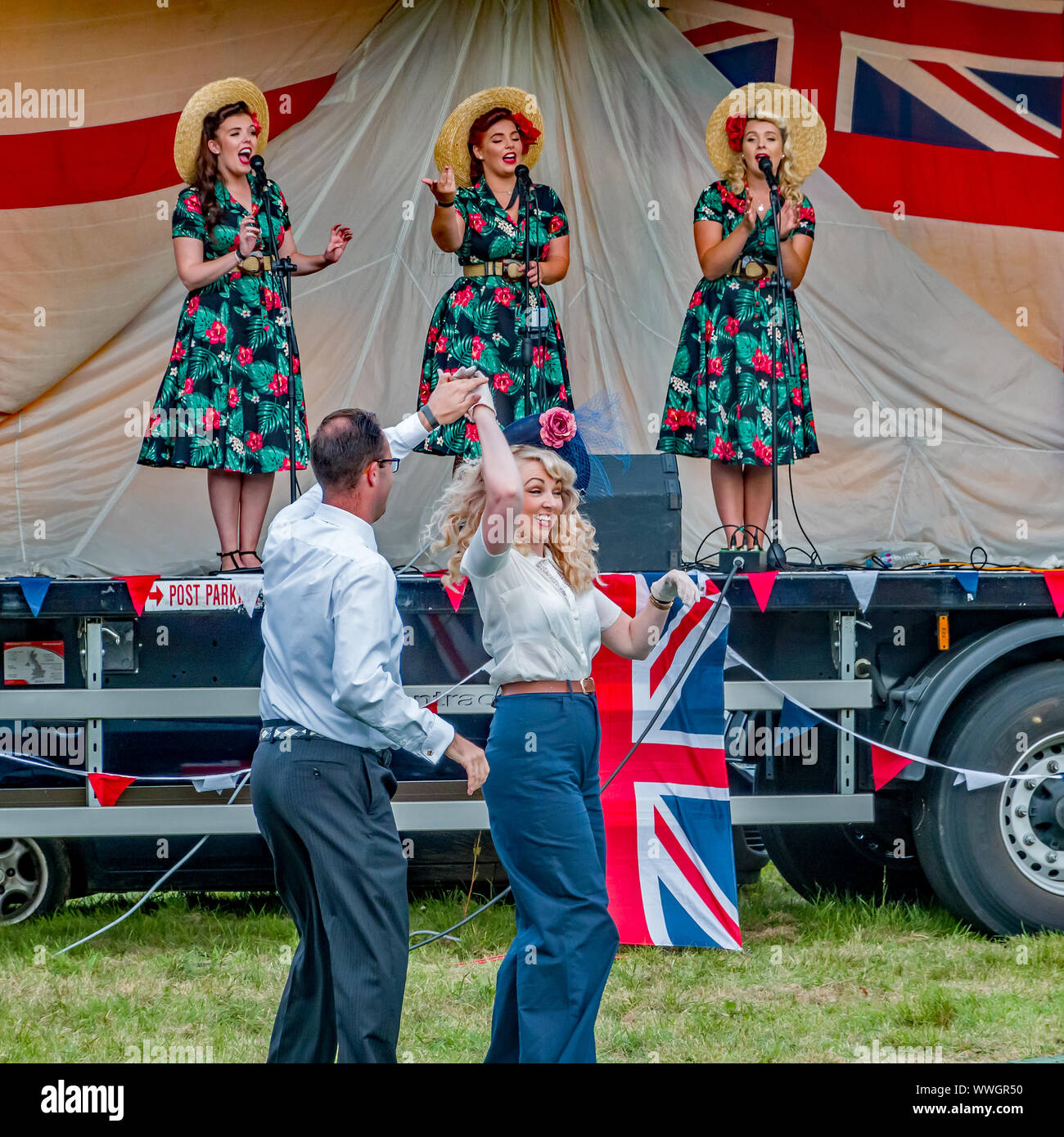 A couple dressed up in 1940s style clothing dancing whilst a female ...