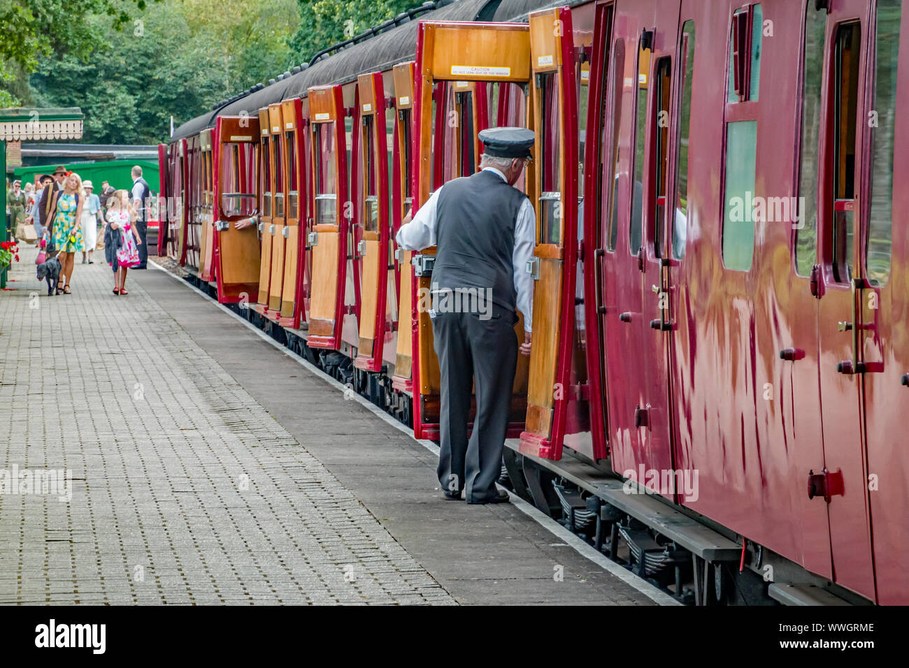 Train conductor dressed in 1940s style clothing checking in passengers ...