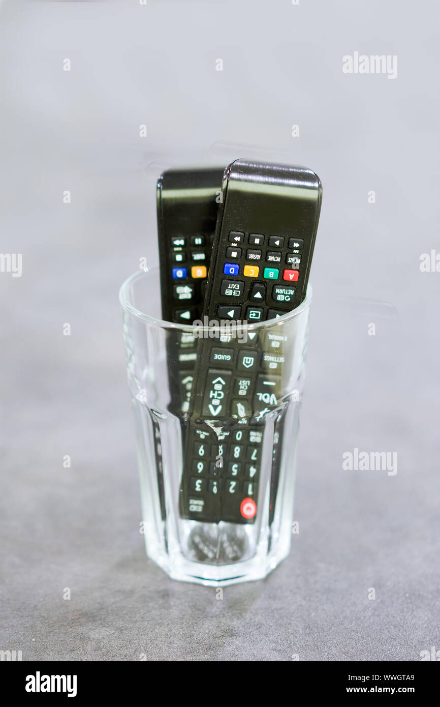 TV remote control in a glass cup on a blurry background Stock Photo - Alamy