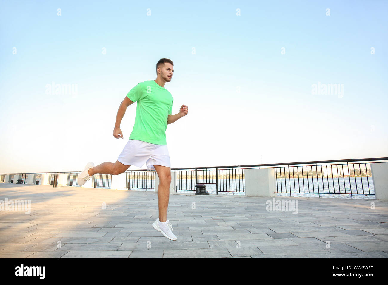 Handsome sporty man running near river Stock Photo - Alamy