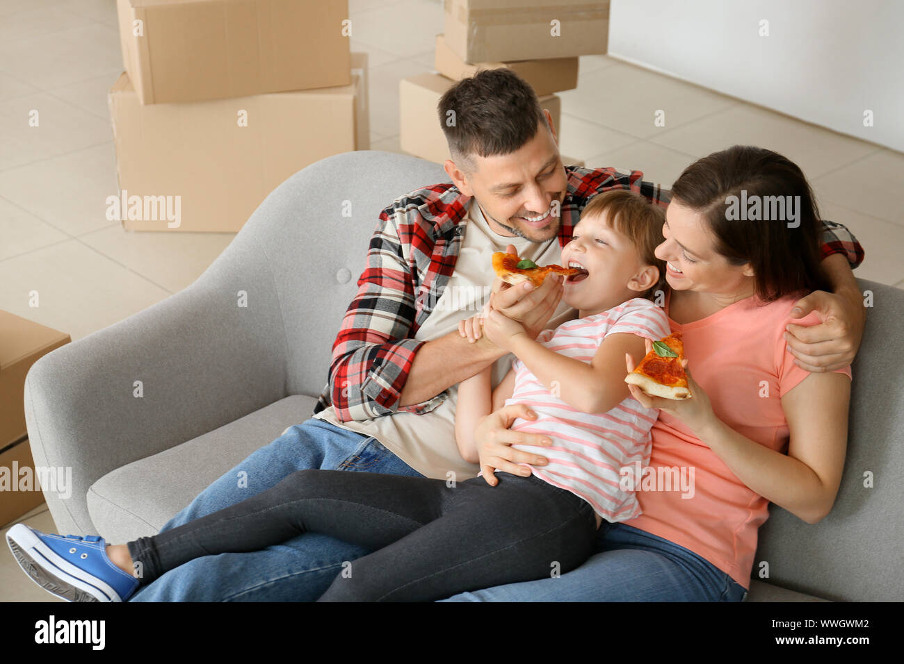 Happy family eating pizza on moving day Stock Photo - Alamy