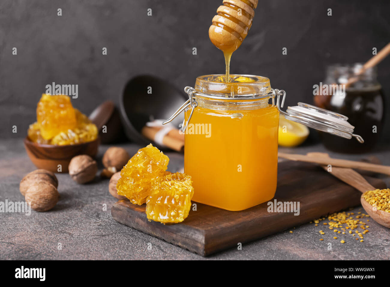 Honey pouring from dipper into jar on table Stock Photo - Alamy