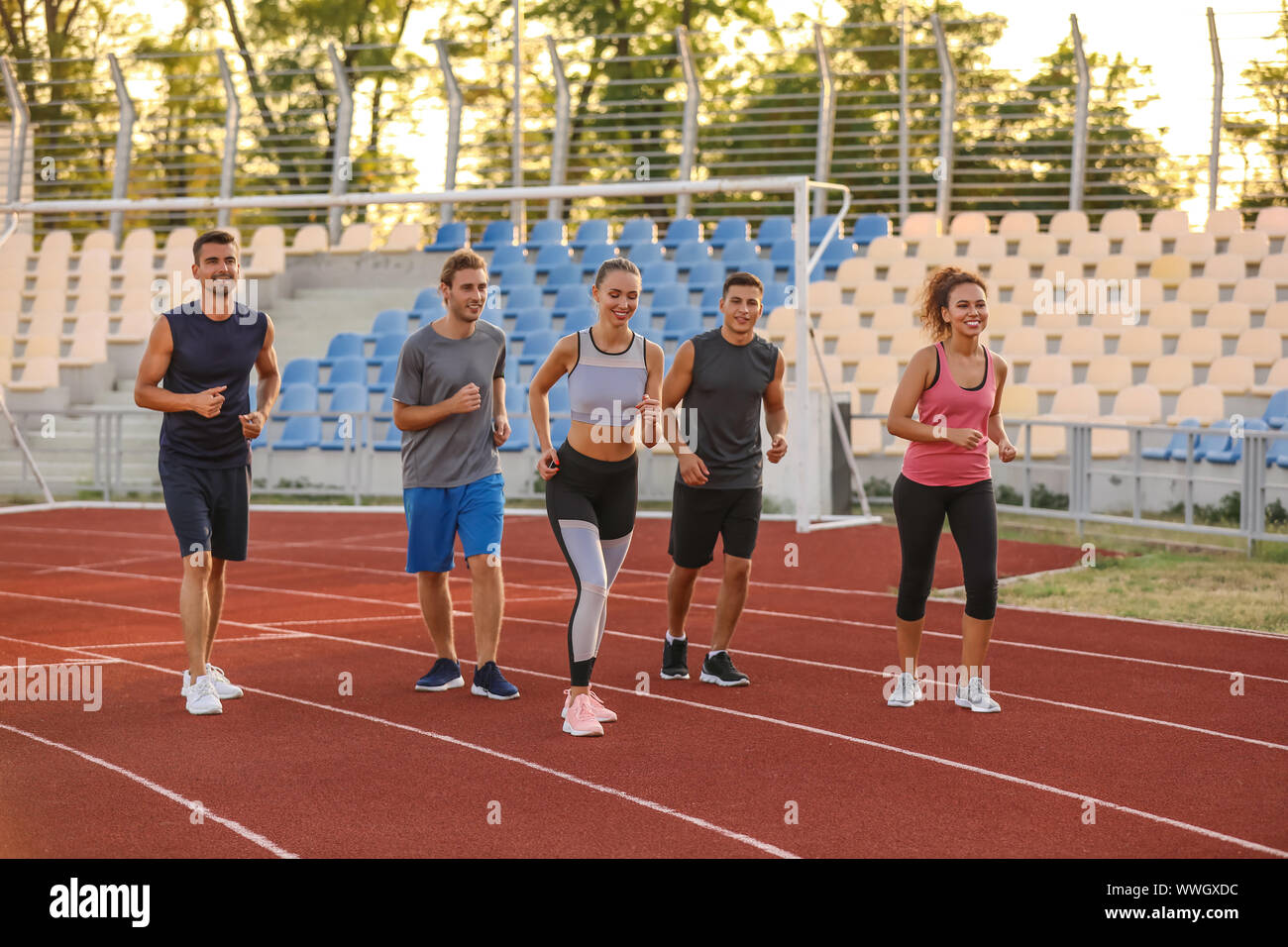 Sporty young people running at the stadium Stock Photo - Alamy