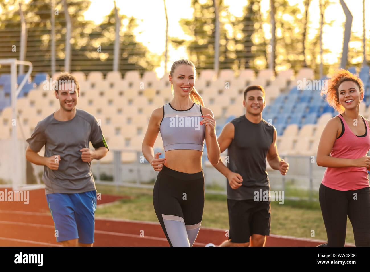 Sporty young people running at the stadium Stock Photo - Alamy