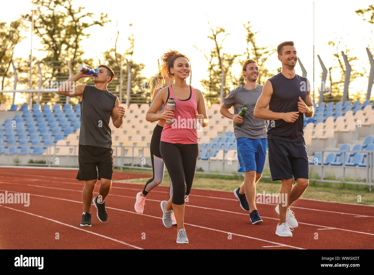 Sporty young people running at the stadium Stock Photo - Alamy