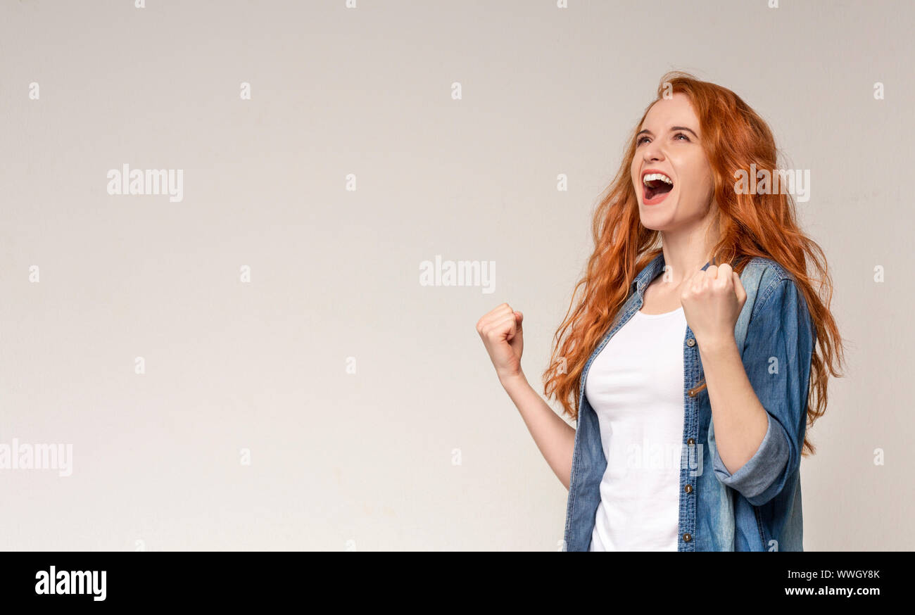 Emotional redhead girl screaming Yes and raising clenched fists Stock ...