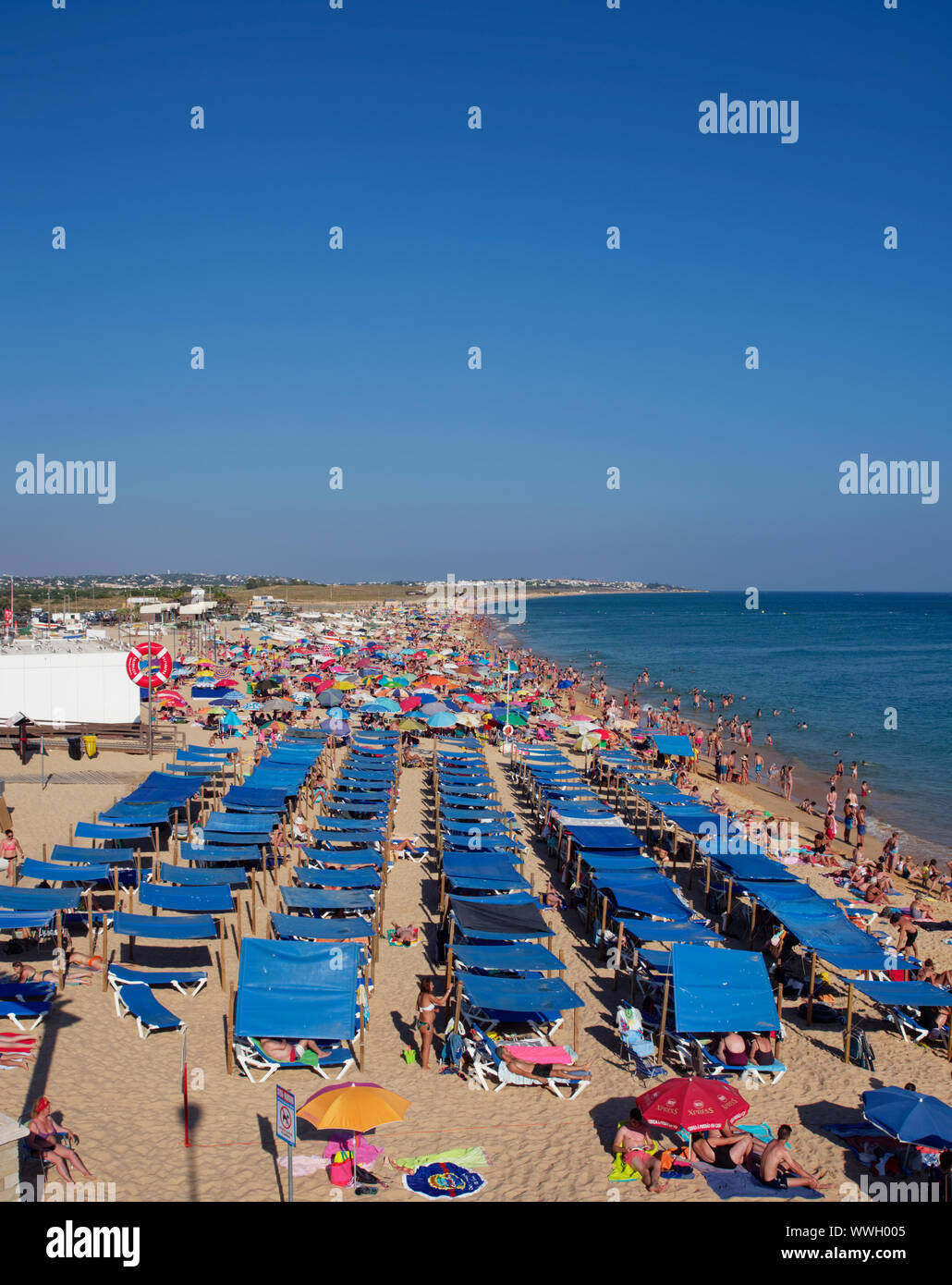 People of all ages enjoying the crowded beach at Faro on the Algarve of ...